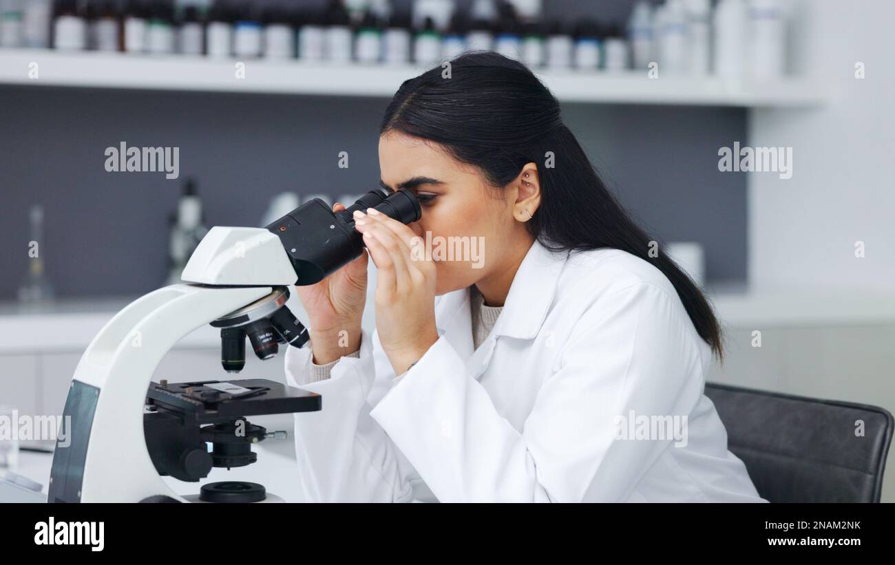Female scientist using a microscope in a research lab. Young biologist ...