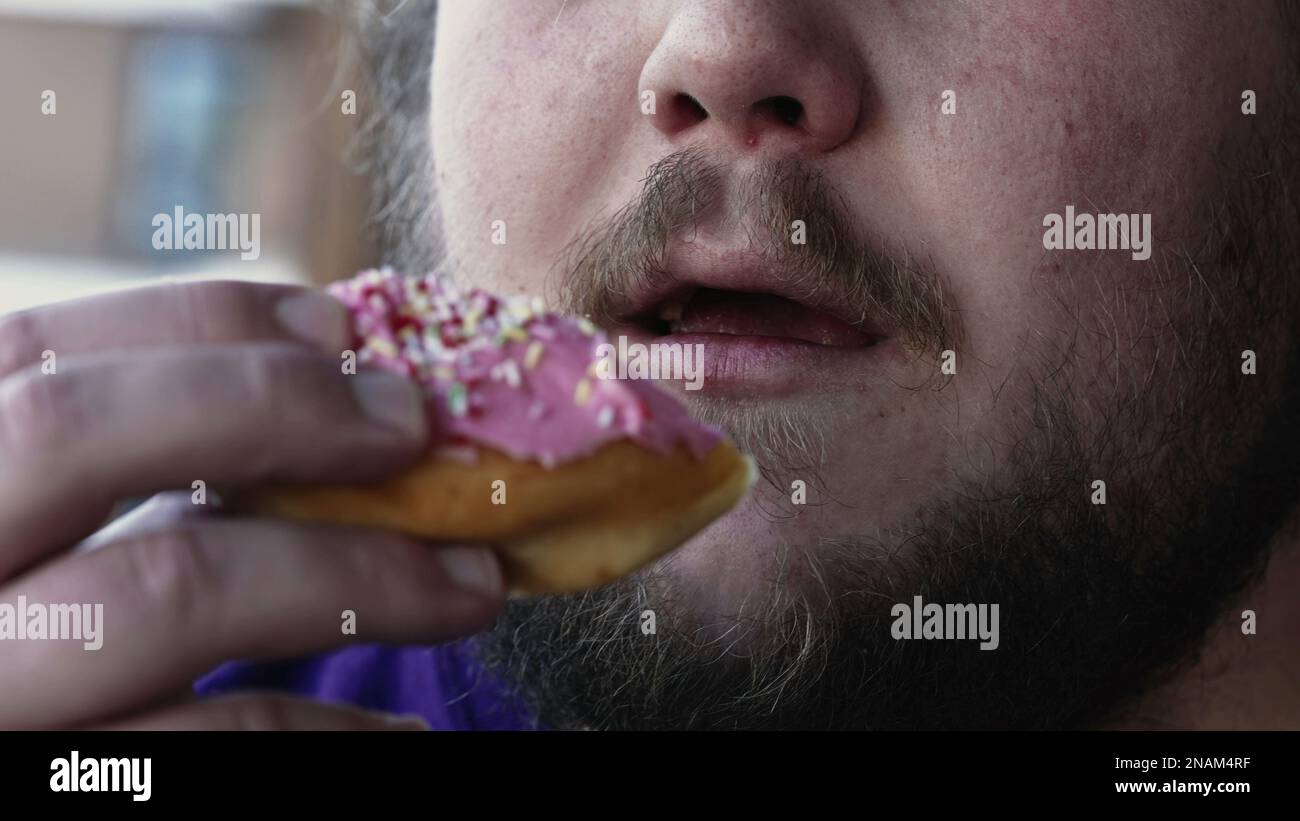 Chubby man eating unhealthy food. Person taking a bite of donut snack ...