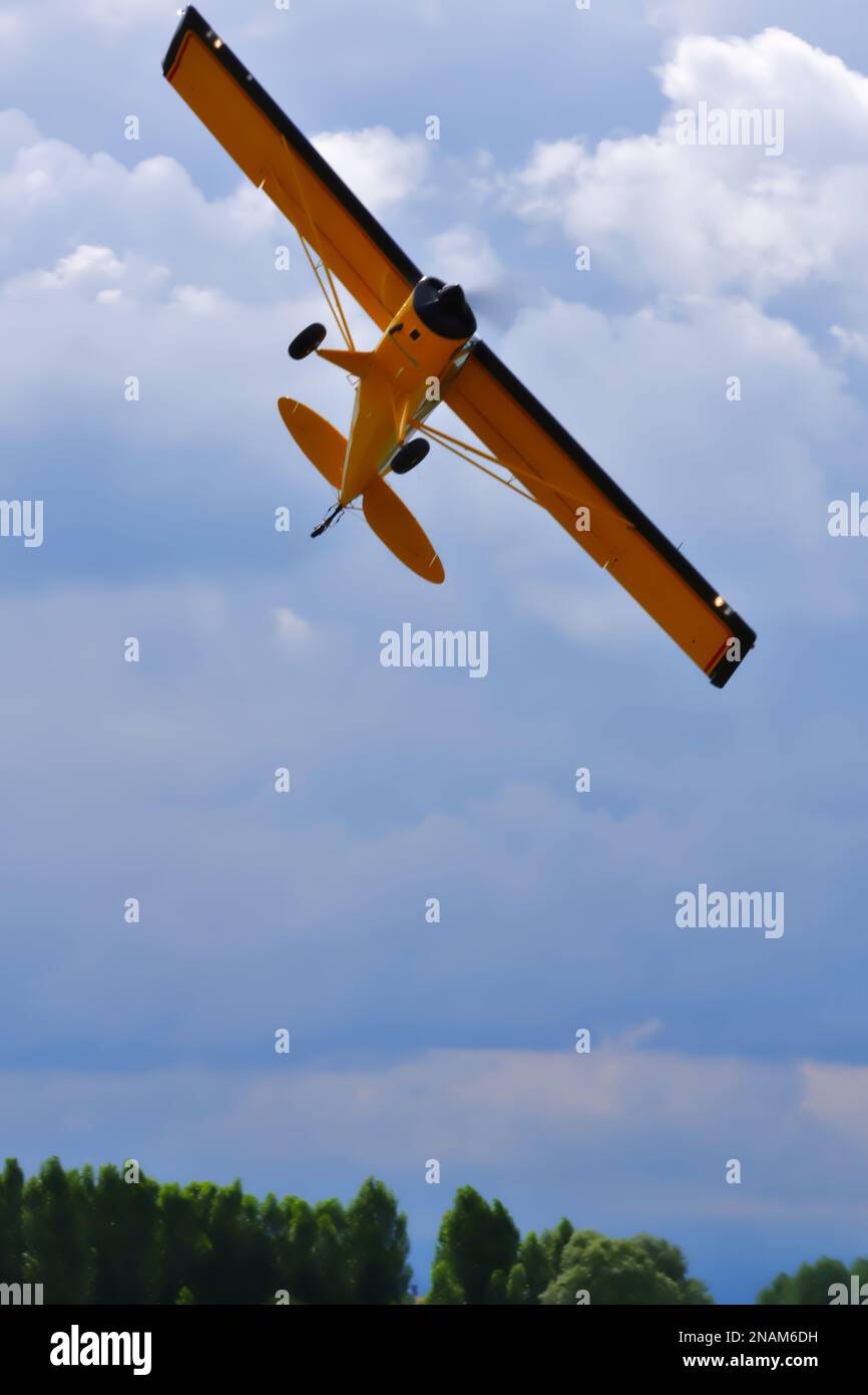 Yellow single engine airplane maneuvering close to the ground with ...
