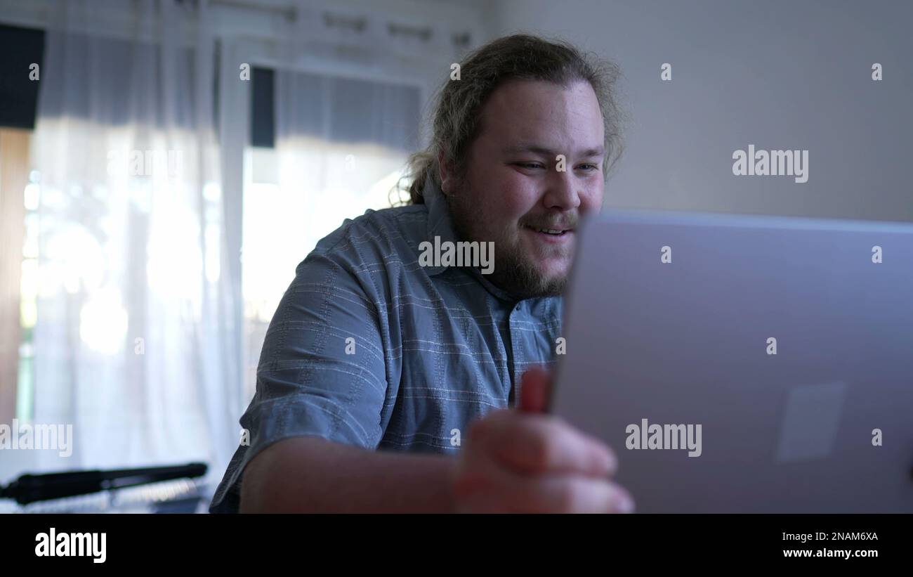 One happy man celebrates success in front of computer. A male chubby ...