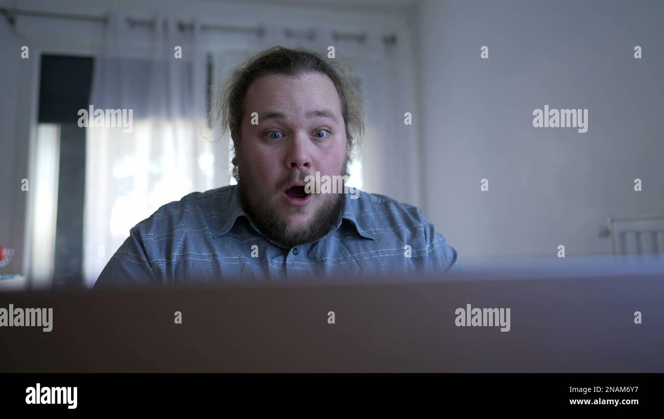 One happy man celebrates success in front of computer. A male chubby ...