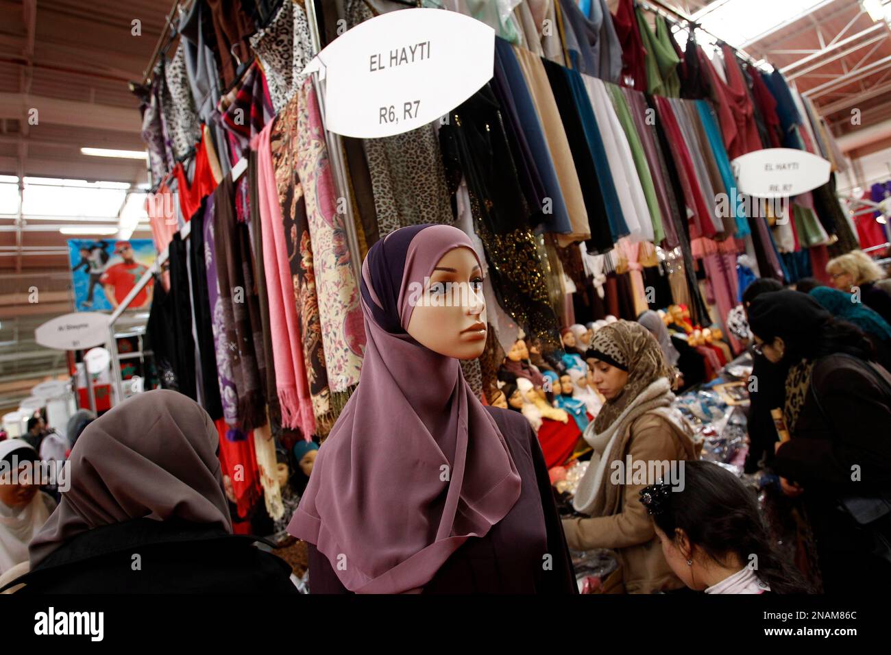 A mannequin with a veil is seen on display as women look at veils at an ...