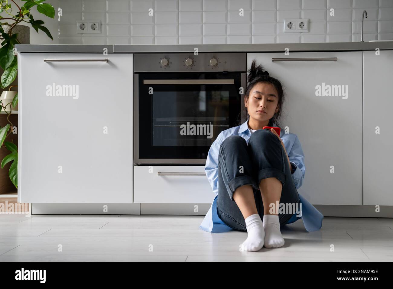 Asian sad girl sit on floor look on screen cellphone after break up or ...