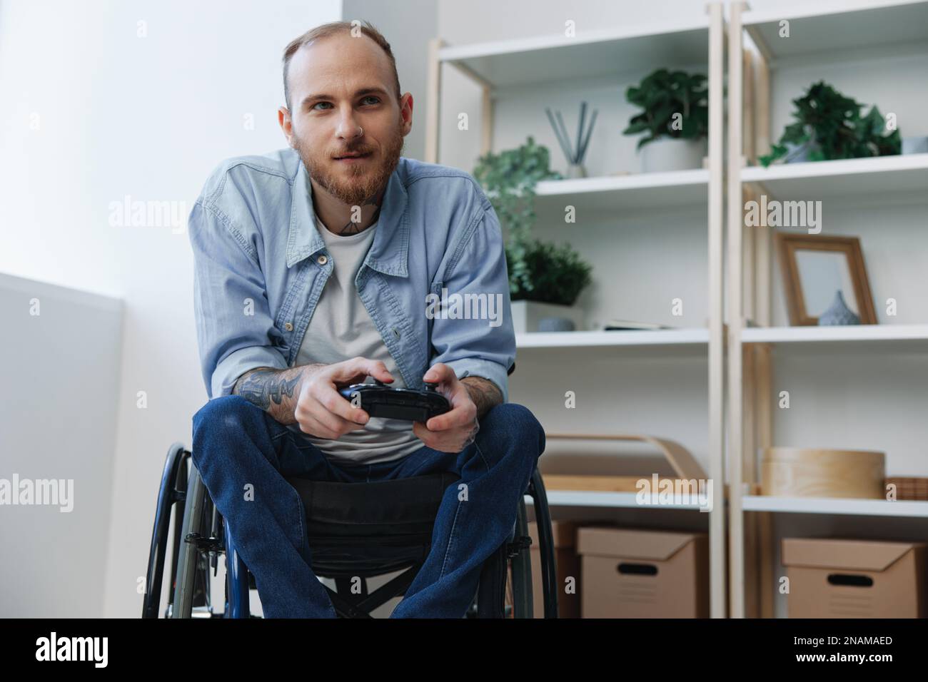 A man in a wheelchair gamer plays games with a joystick in his hands at ...