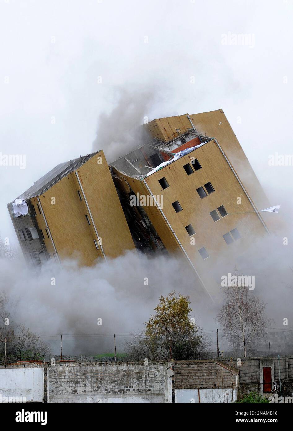 A building collapses in a cloud of dust and water while being imploded ...