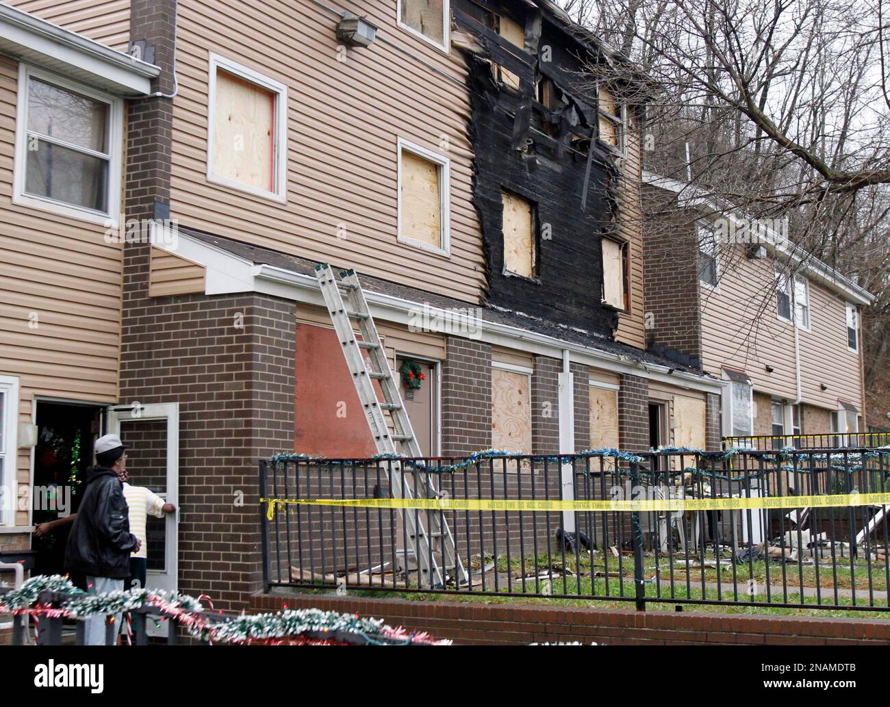 Neighbors look out their door at the apartment where a fire killed a ...