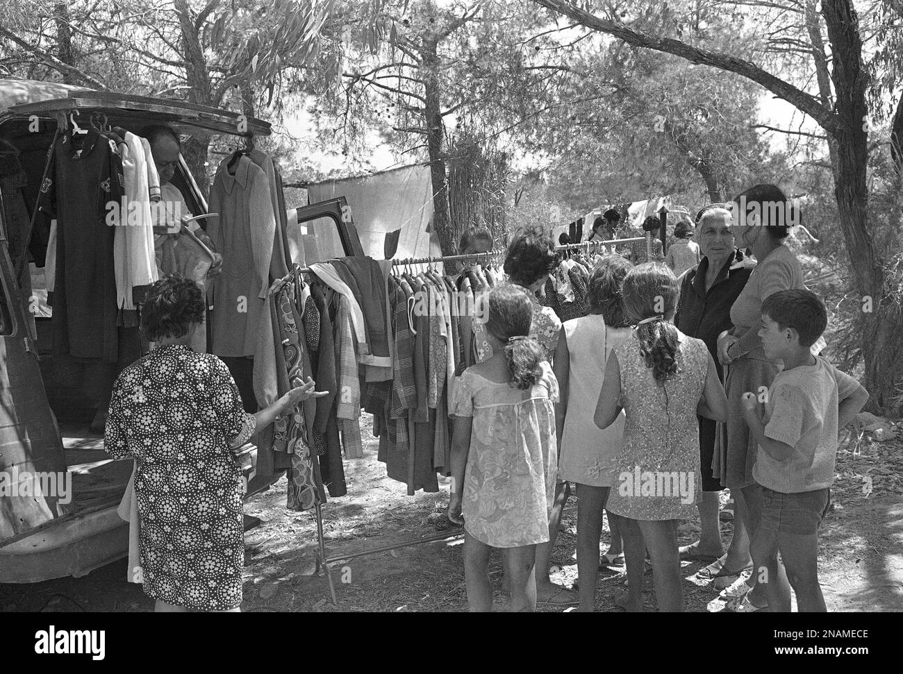 Greek Cypriot refugee children stand near outdoor clothing racks inside ...