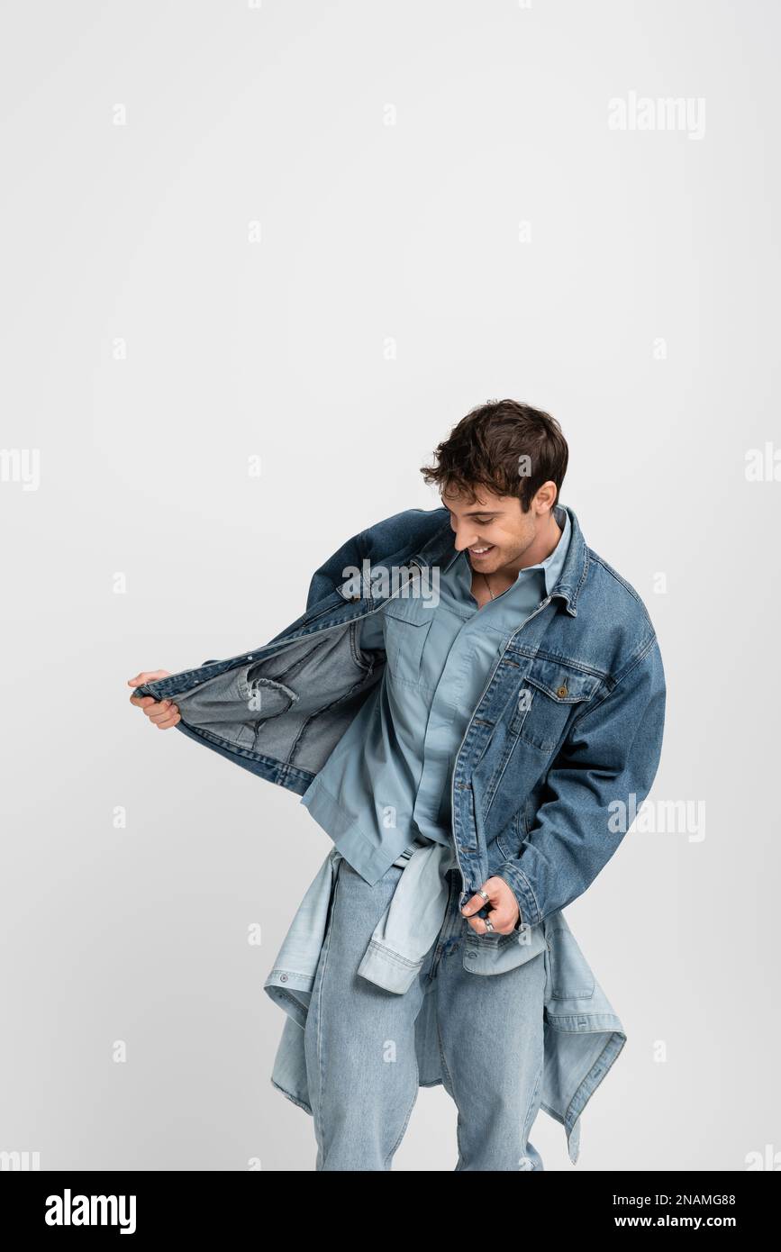 happy young man in denim outfit posing while adjusting jacket isolated ...