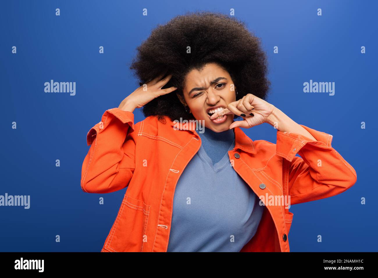 Stylish african american woman winking and biting finger isolated on ...