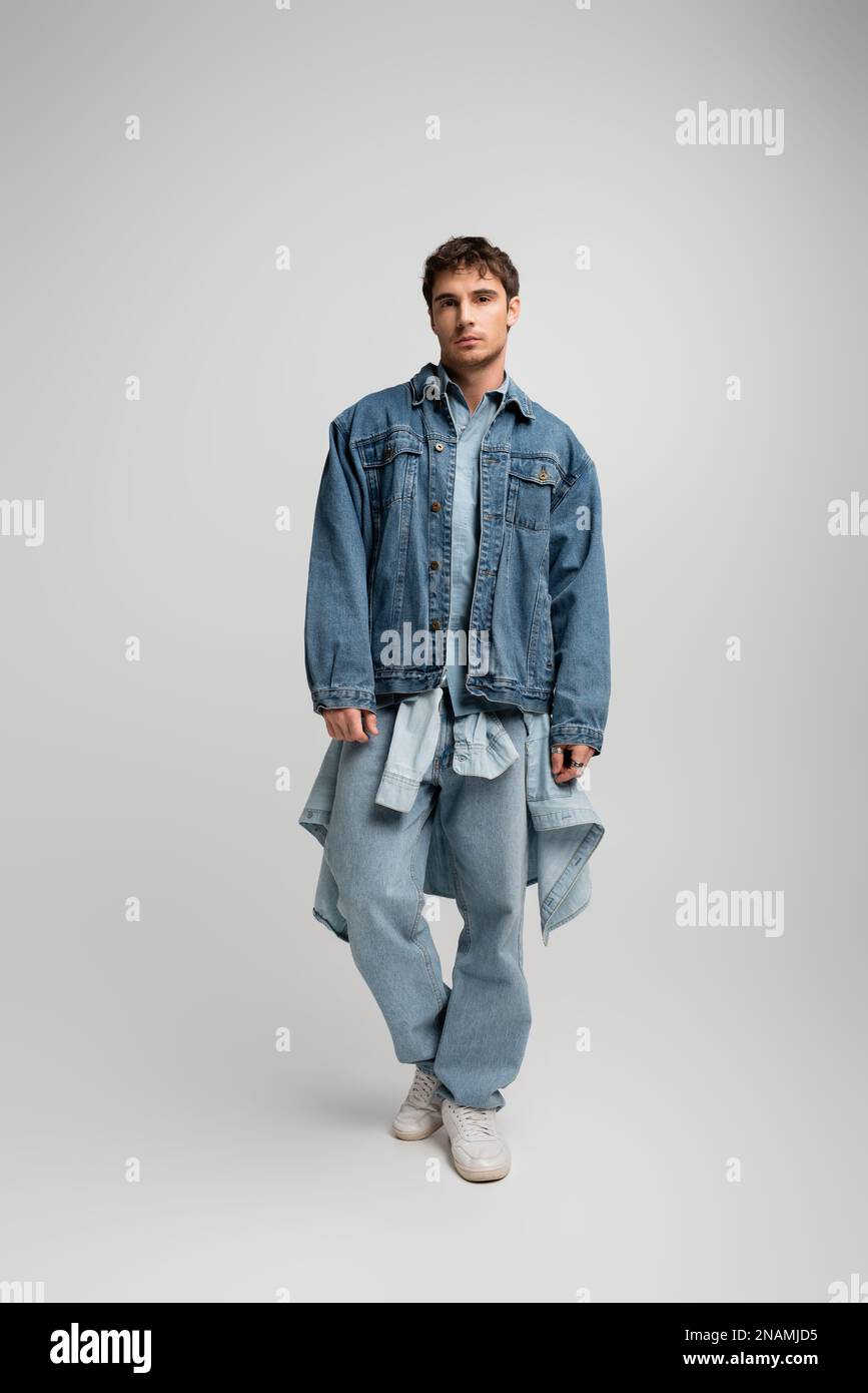 full length of young man in denim outfit posing and looking at camera ...
