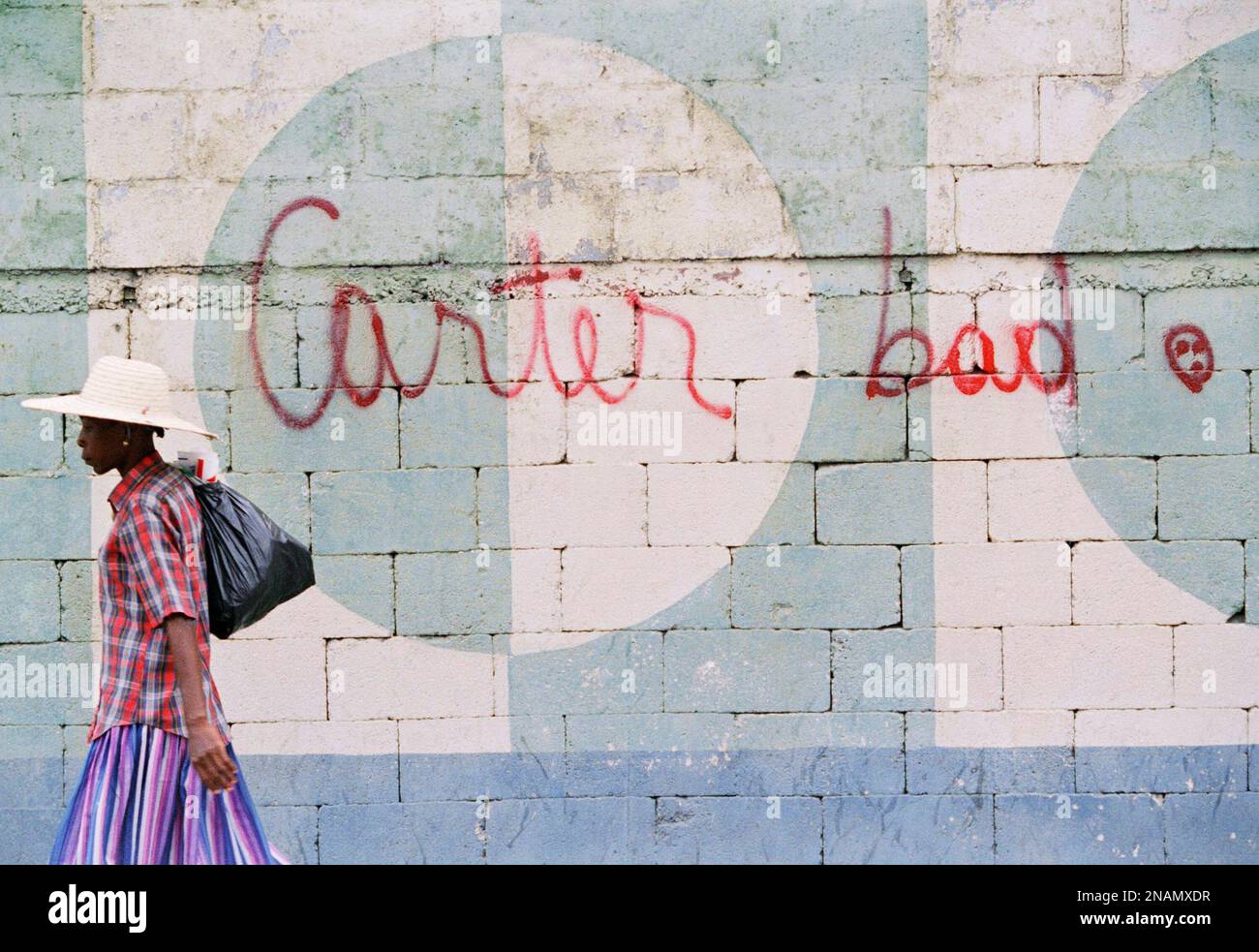 A woman walks past anti-Carter graffiti in Port-au-Prince, Haiti , Feb ...