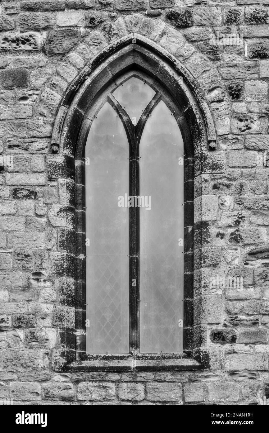 A vertical shot of medieval gothic-style arch church window, grayscale ...
