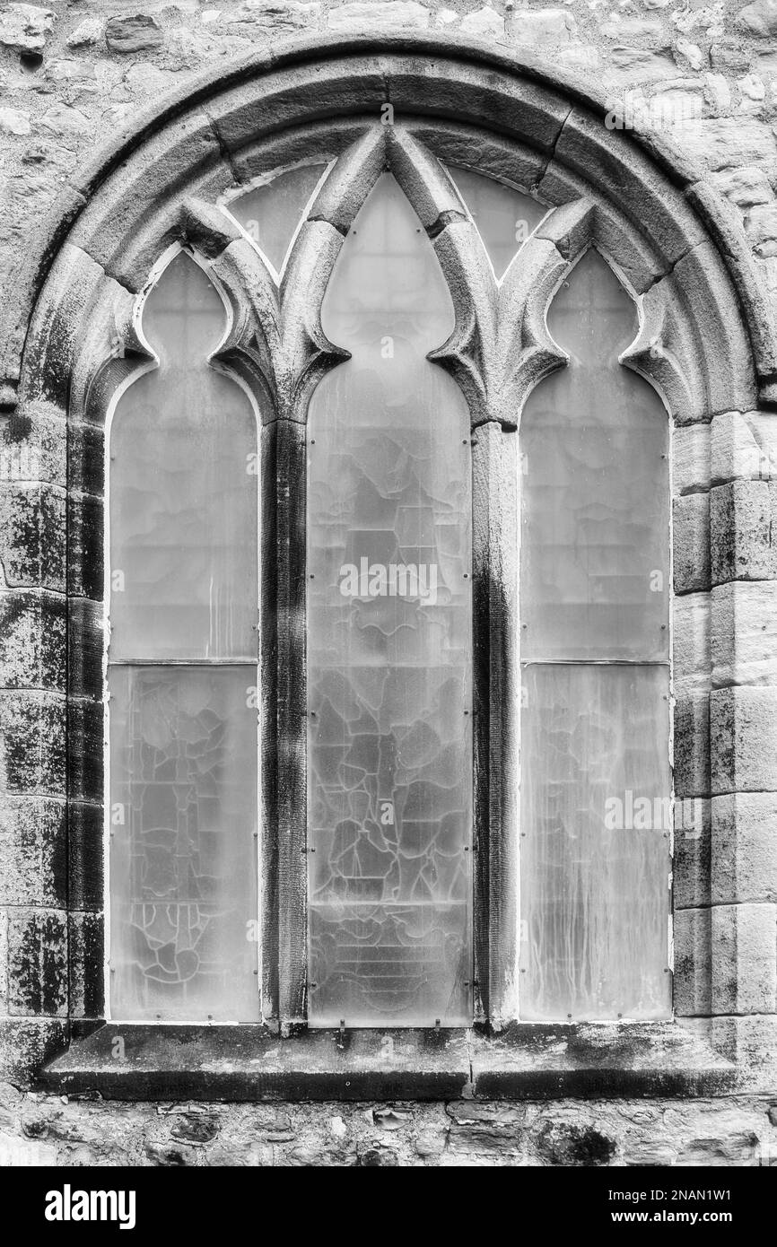 A vertical shot of medieval gothic-style arch church window, grayscale ...