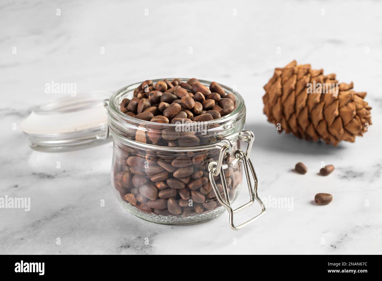Pine nuts in a jar and a pine cone in the kitchen on a light background ...