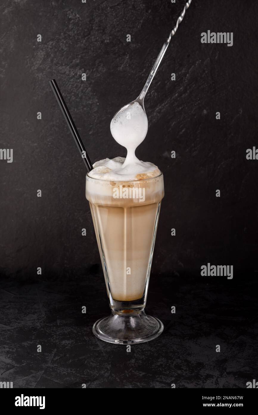 close-up of a barista preparing coffee with syrup and cream foam in a ...
