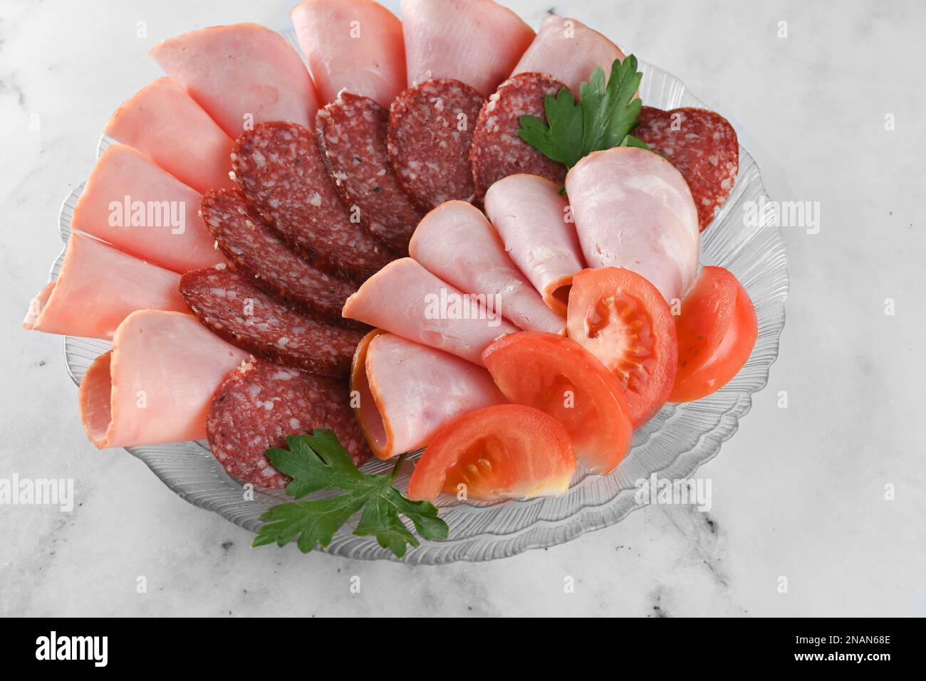 plate with an assortment of boiled, smoked sausage on bright table ...