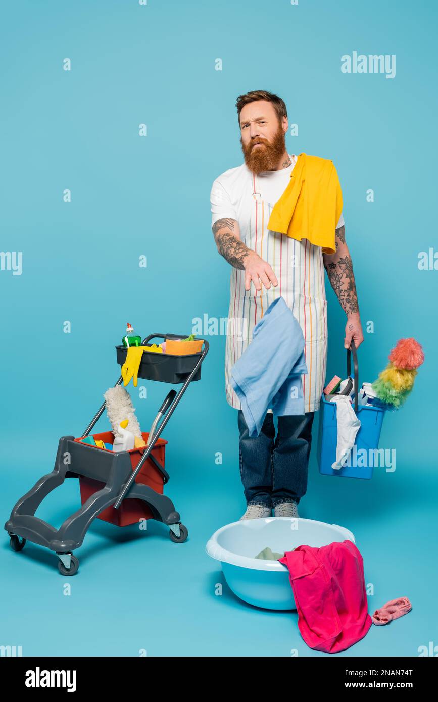 displeased man with garments and bucket pointing at laundry bowl near ...
