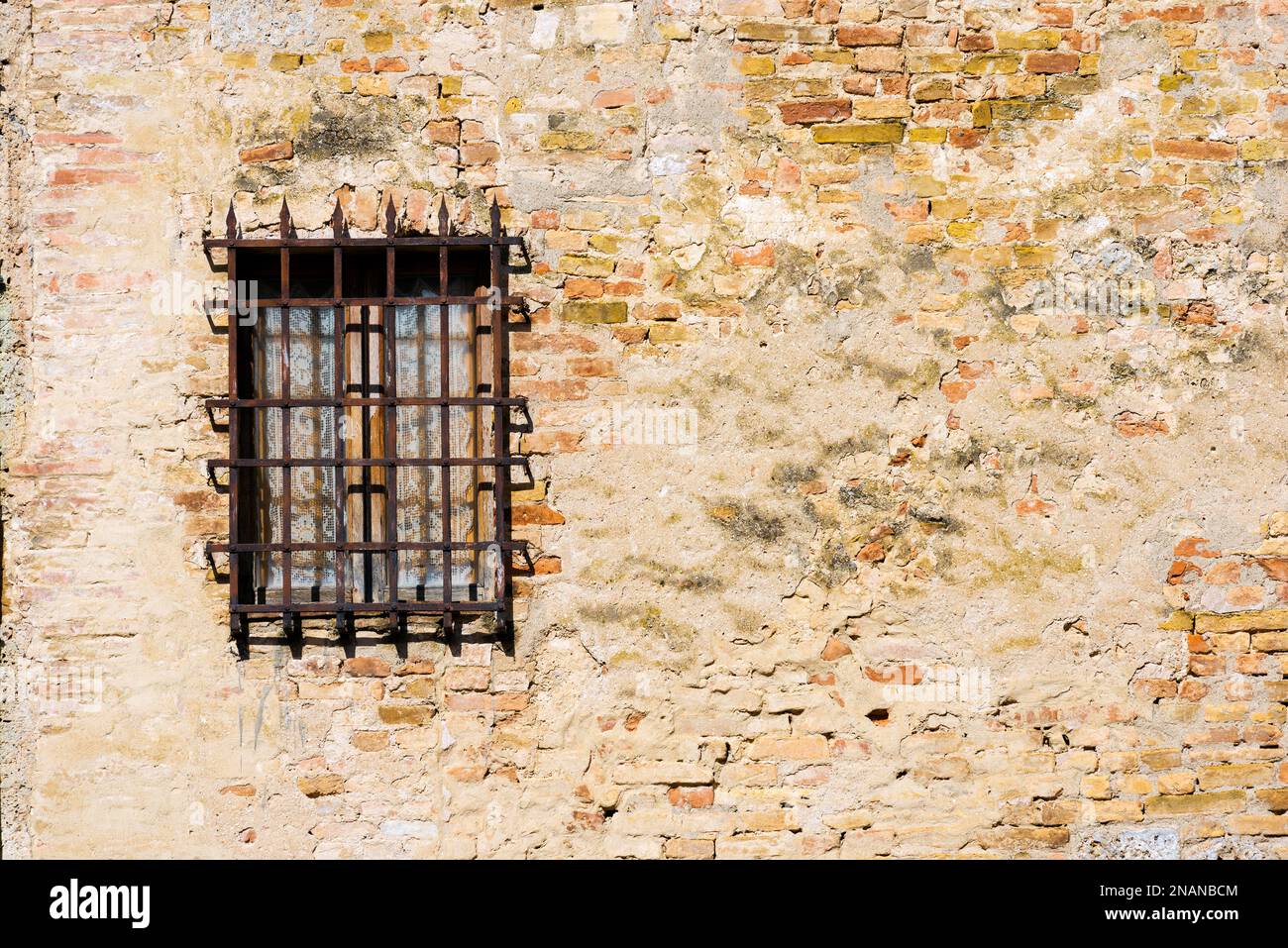 Detail of a window with an old and rusty grating on a old wall with ...