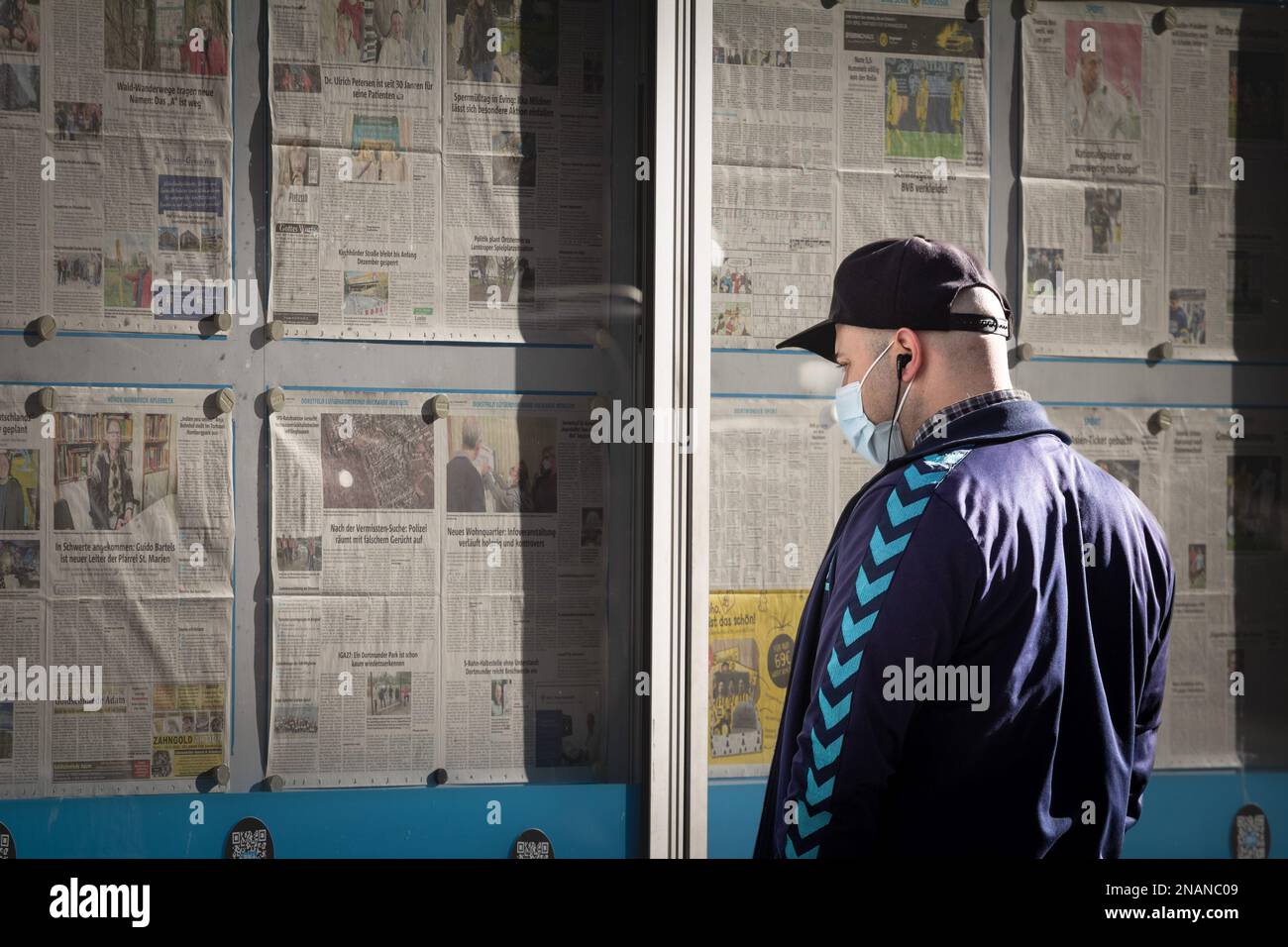 Picture of a man reading newspaper in streets Cologne, wearing face ...