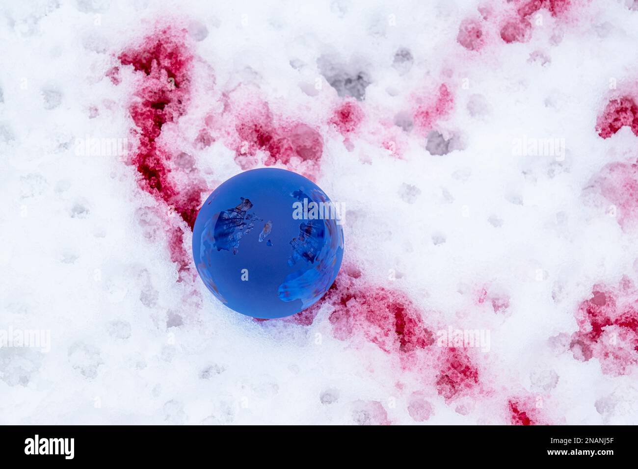 The concept of symbolism. crystal earth globe on snow with blood stains ...