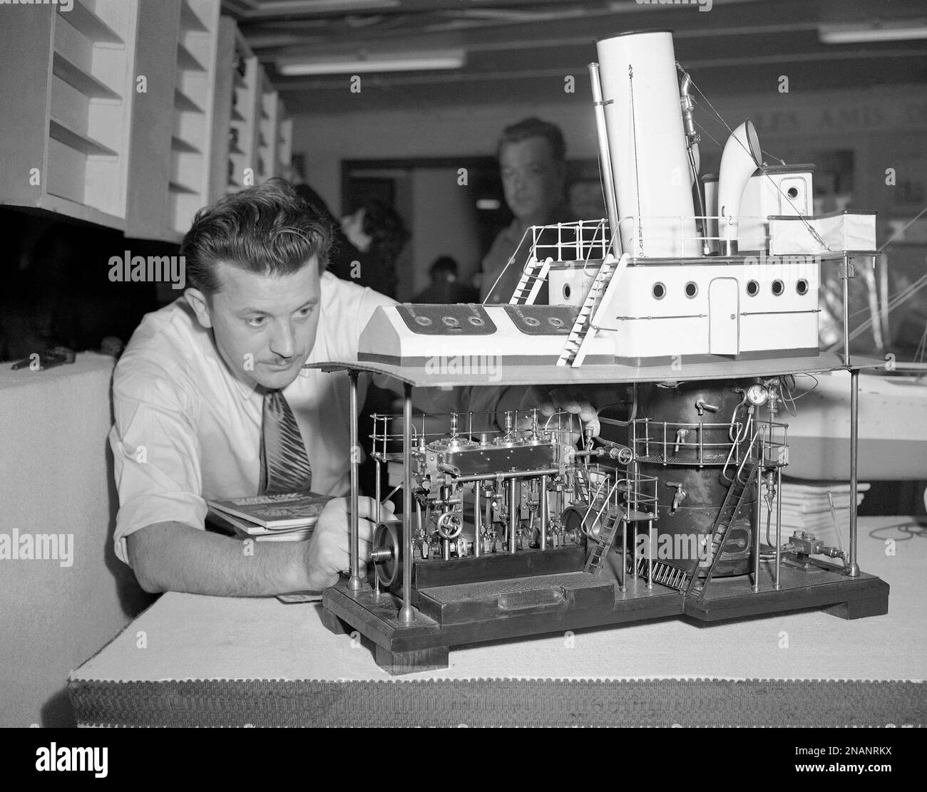 An exhibitor looks over his working model of a steam engine, one of the ...