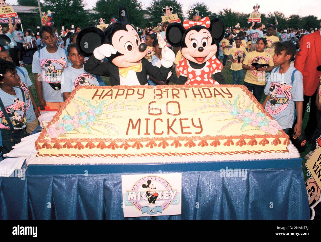 Mickey and Minnie Mouse take turns cutting Mickey’s birthday cake ...