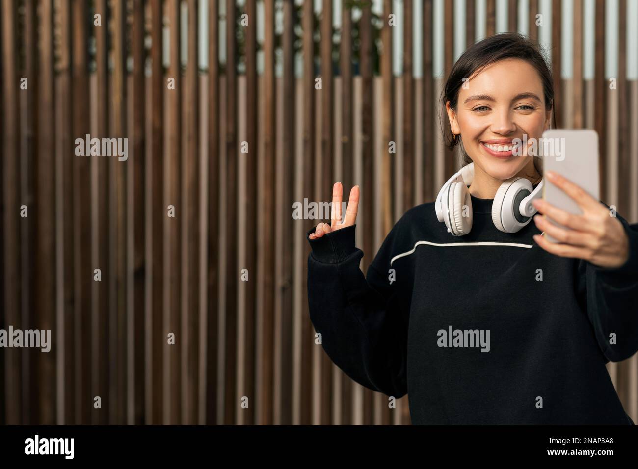 Smiling caucasian millennial lady in sportswear, headphones makes ...