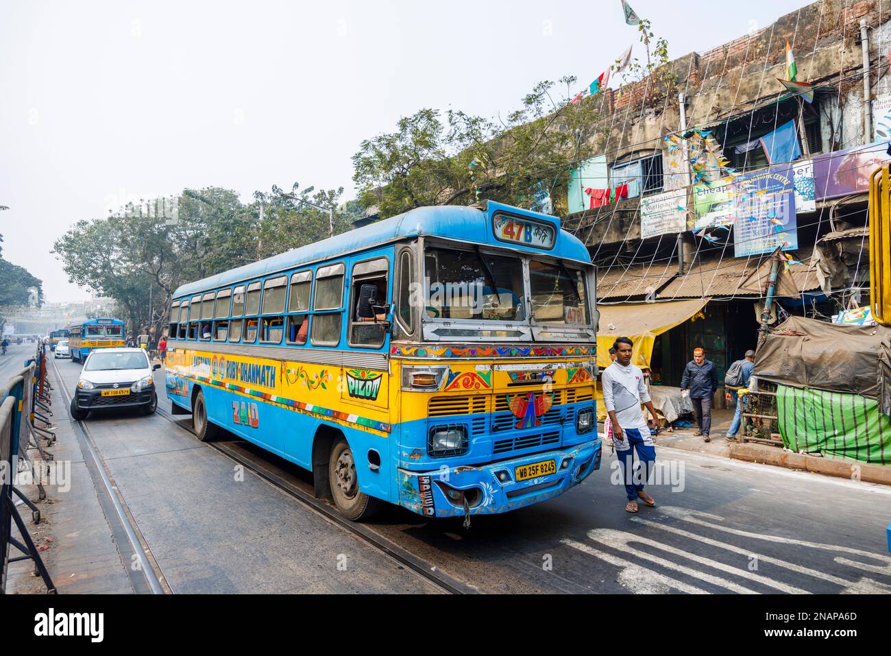 Street scene with a bus passing shops, stalls and kiosks in the ...