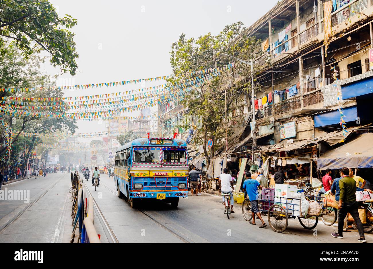 Street scene with a bus passing shops, stalls and kiosks in the ...