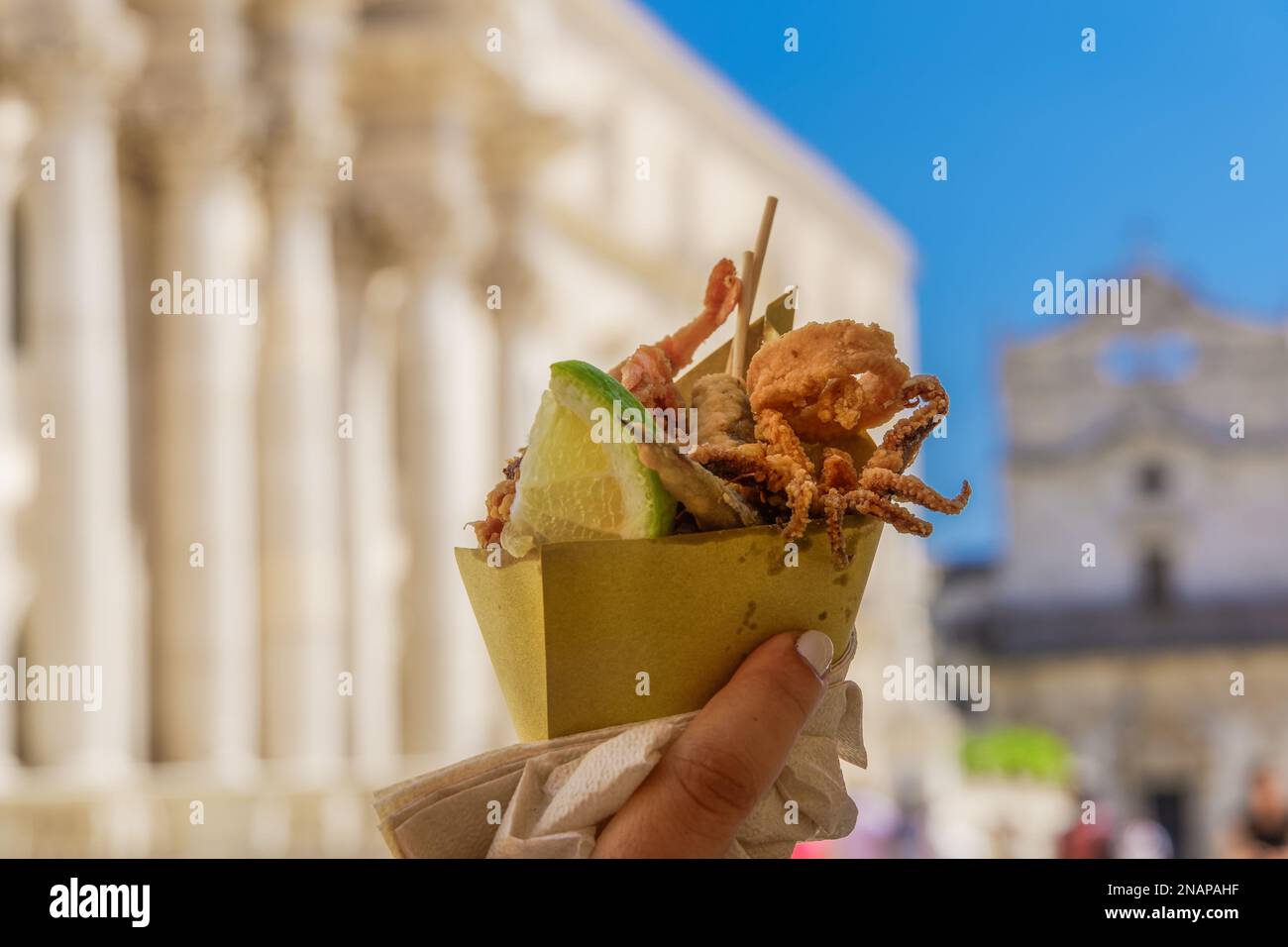 Holding Italian street fish food on a cone. A female hand that holds a ...