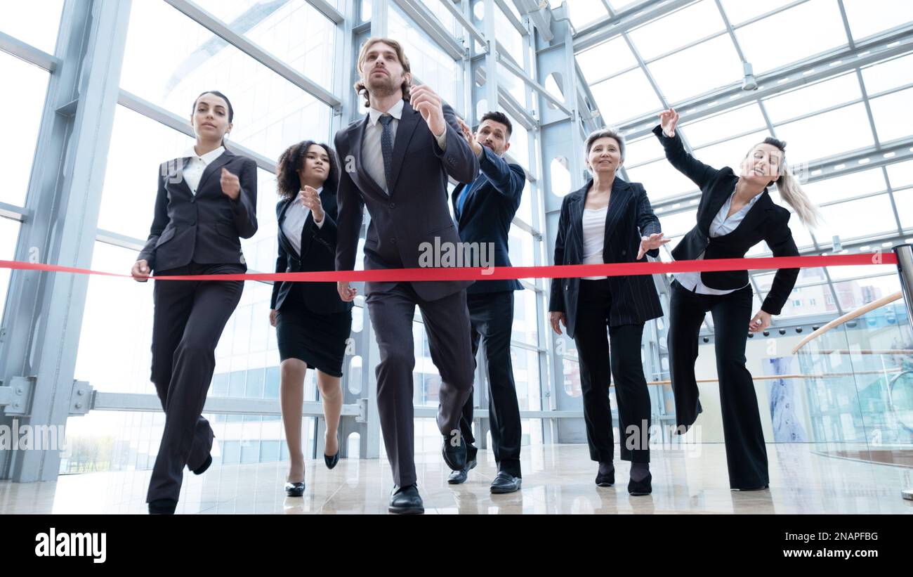 Group of happy business people running in office building crossing red ...