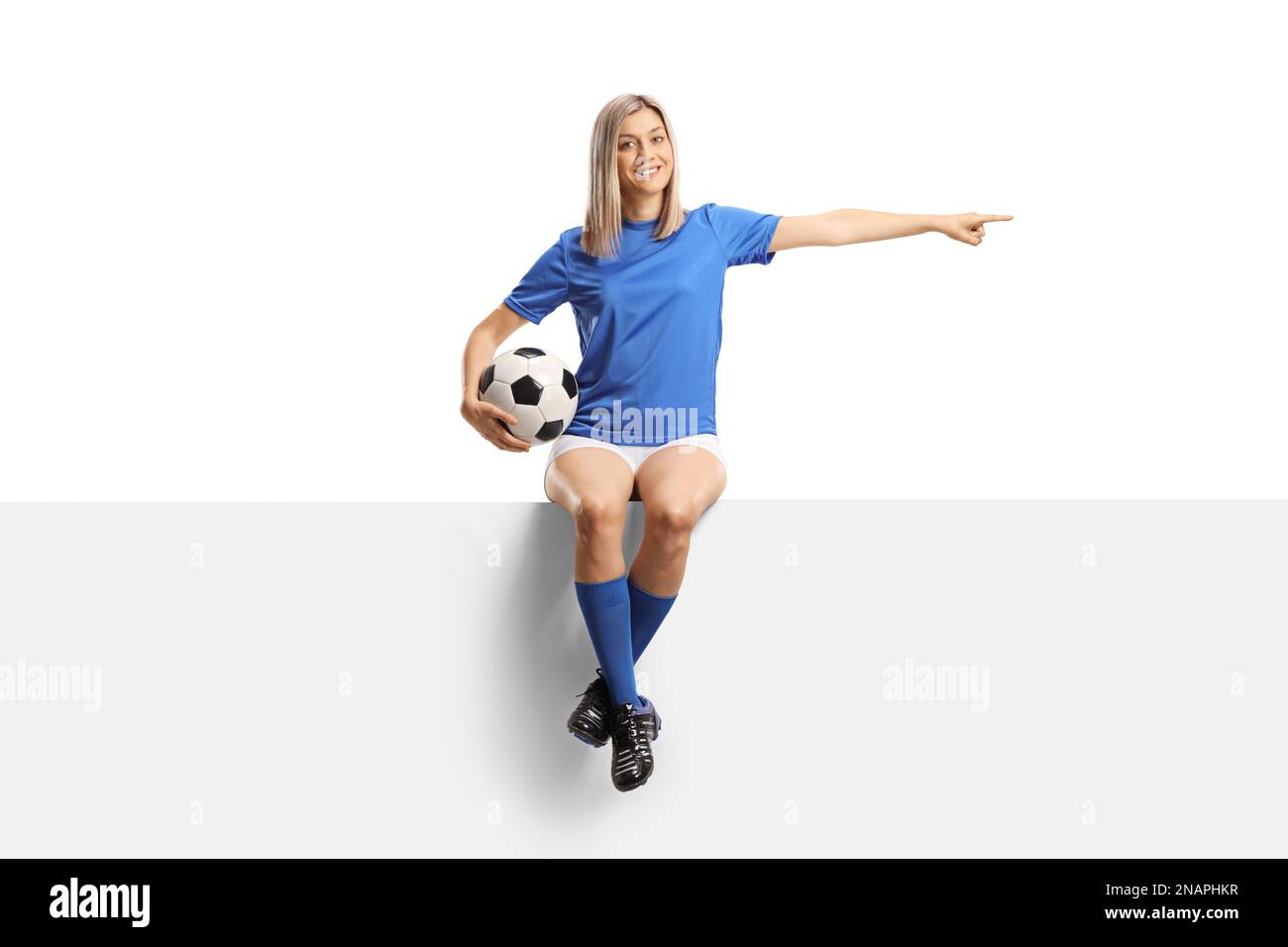 Full length portrait of a female football player sitting on a blank ...