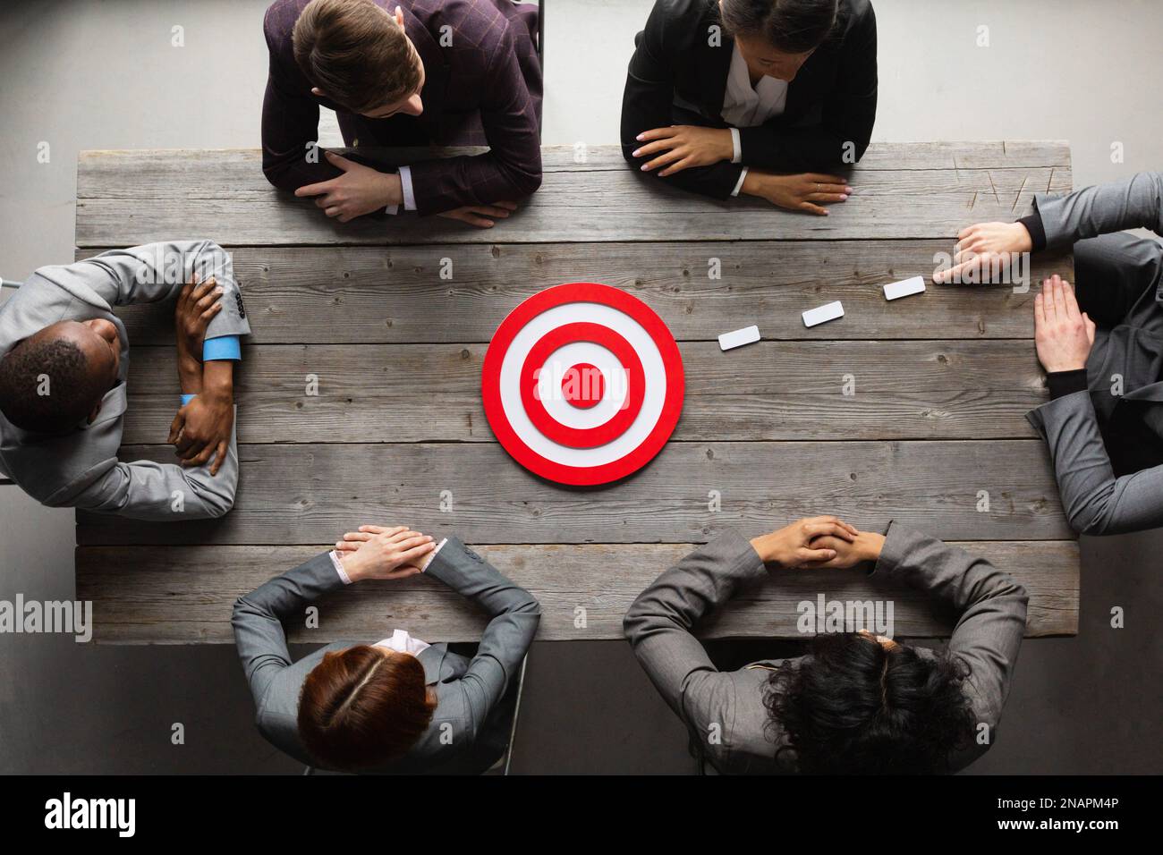 Team of business people pointing at red target at meeting table Stock ...