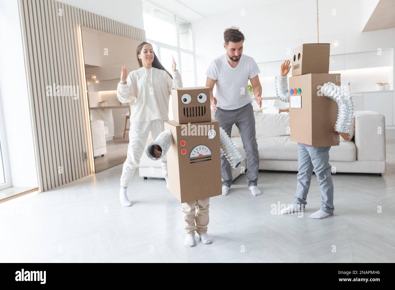 Happy family of parents and two children playing dancing like robots at ...