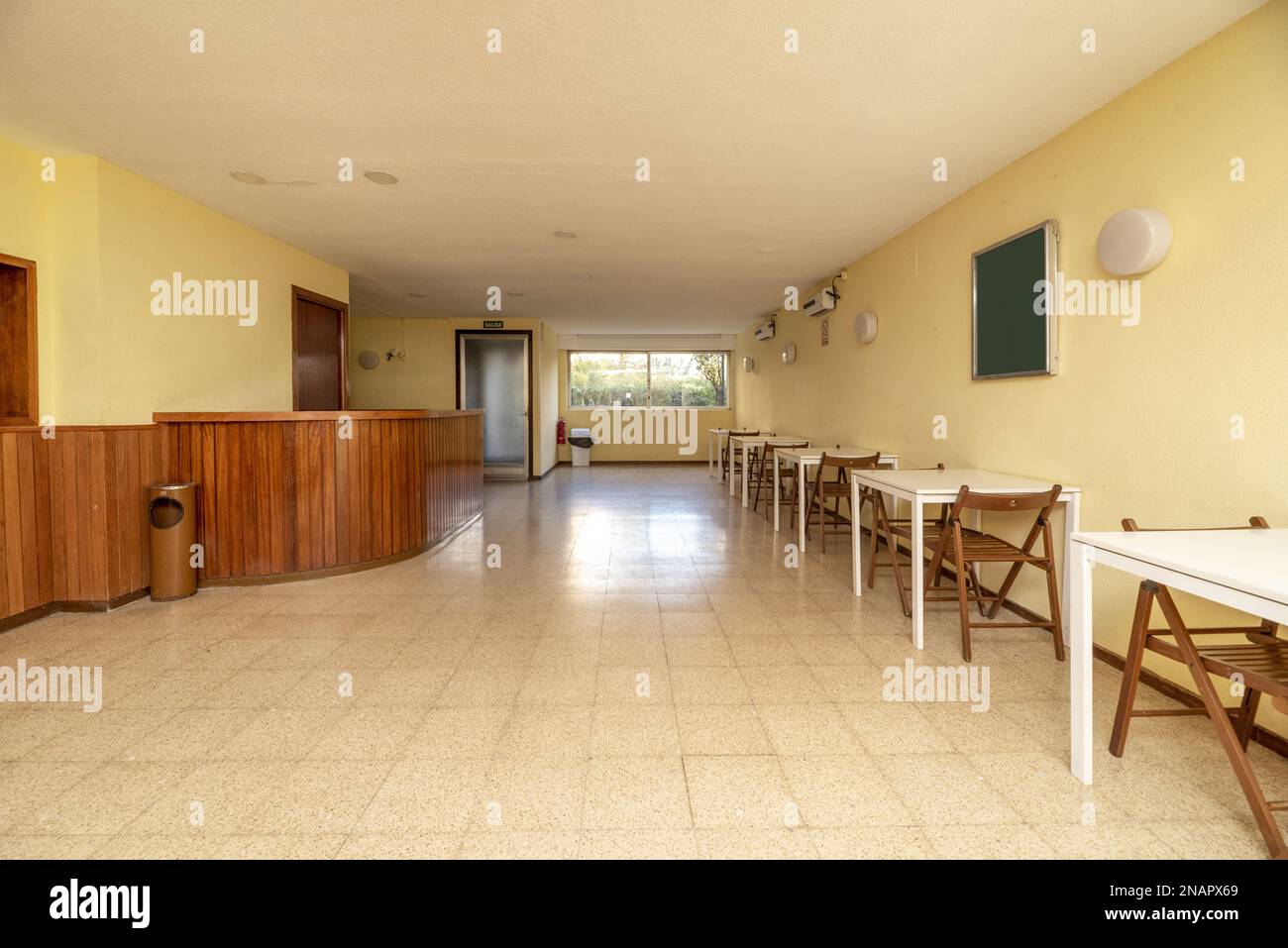 Large community room in a building with white wooden tables with ...