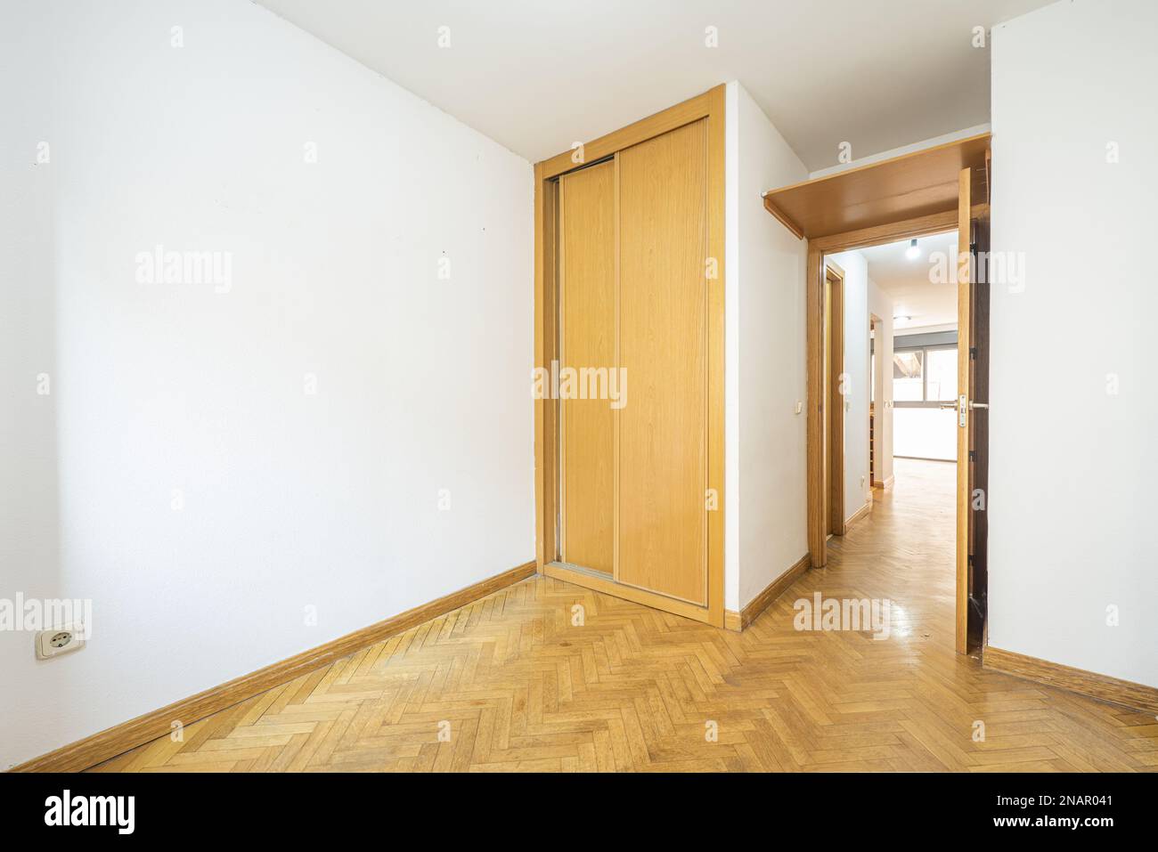 An empty room with a built-in wardrobe with oak sliding doors and ...