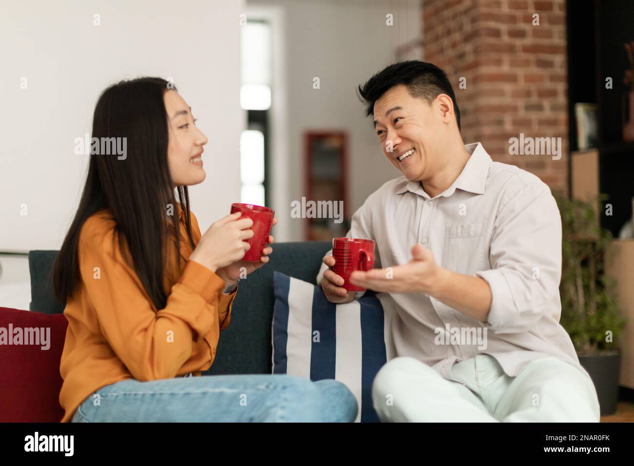Loving korean couple drinking coffee and talking, enjoying free time ...