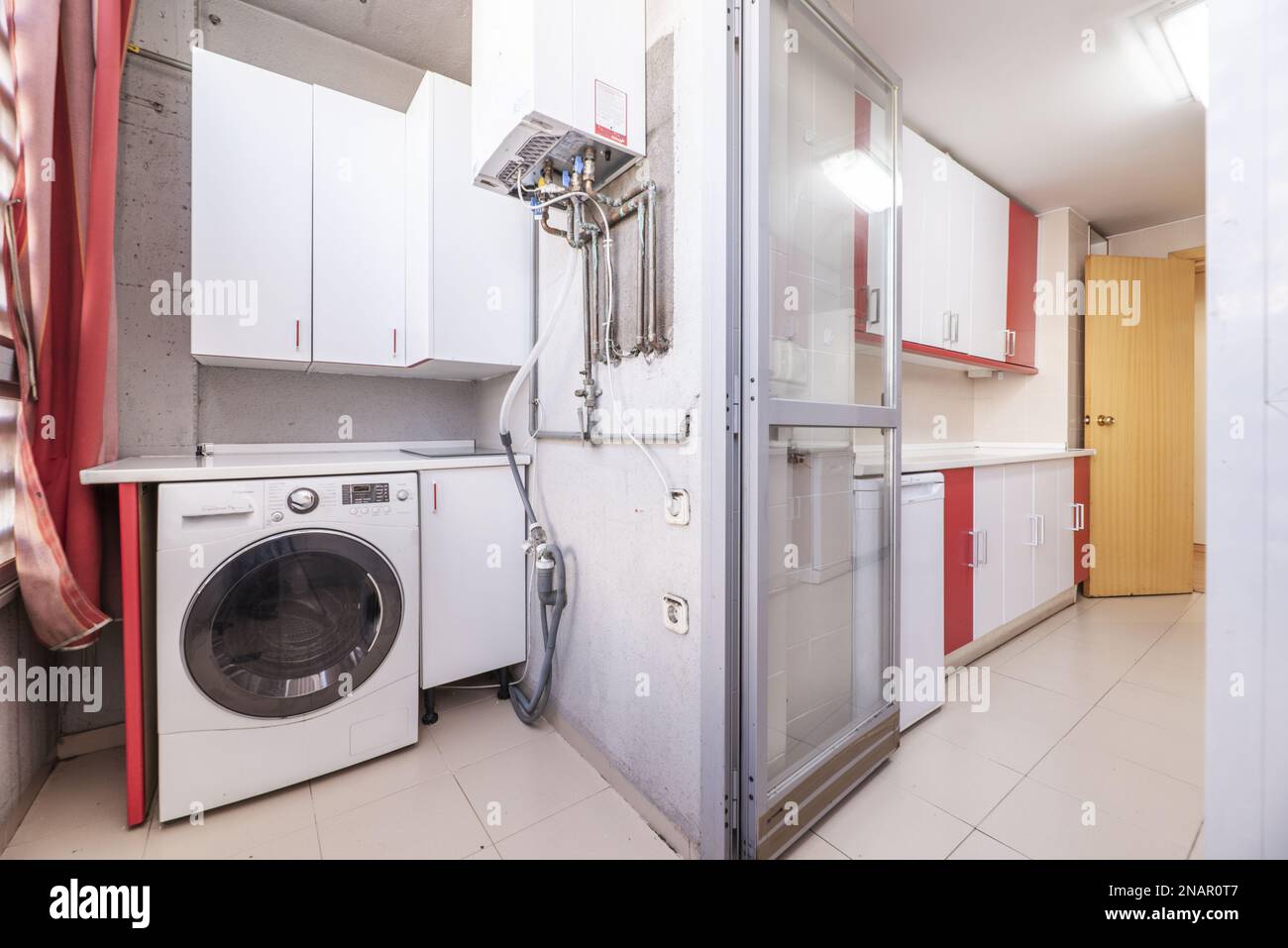 utility room with a kitchen with a washing machine, storage units and a ...