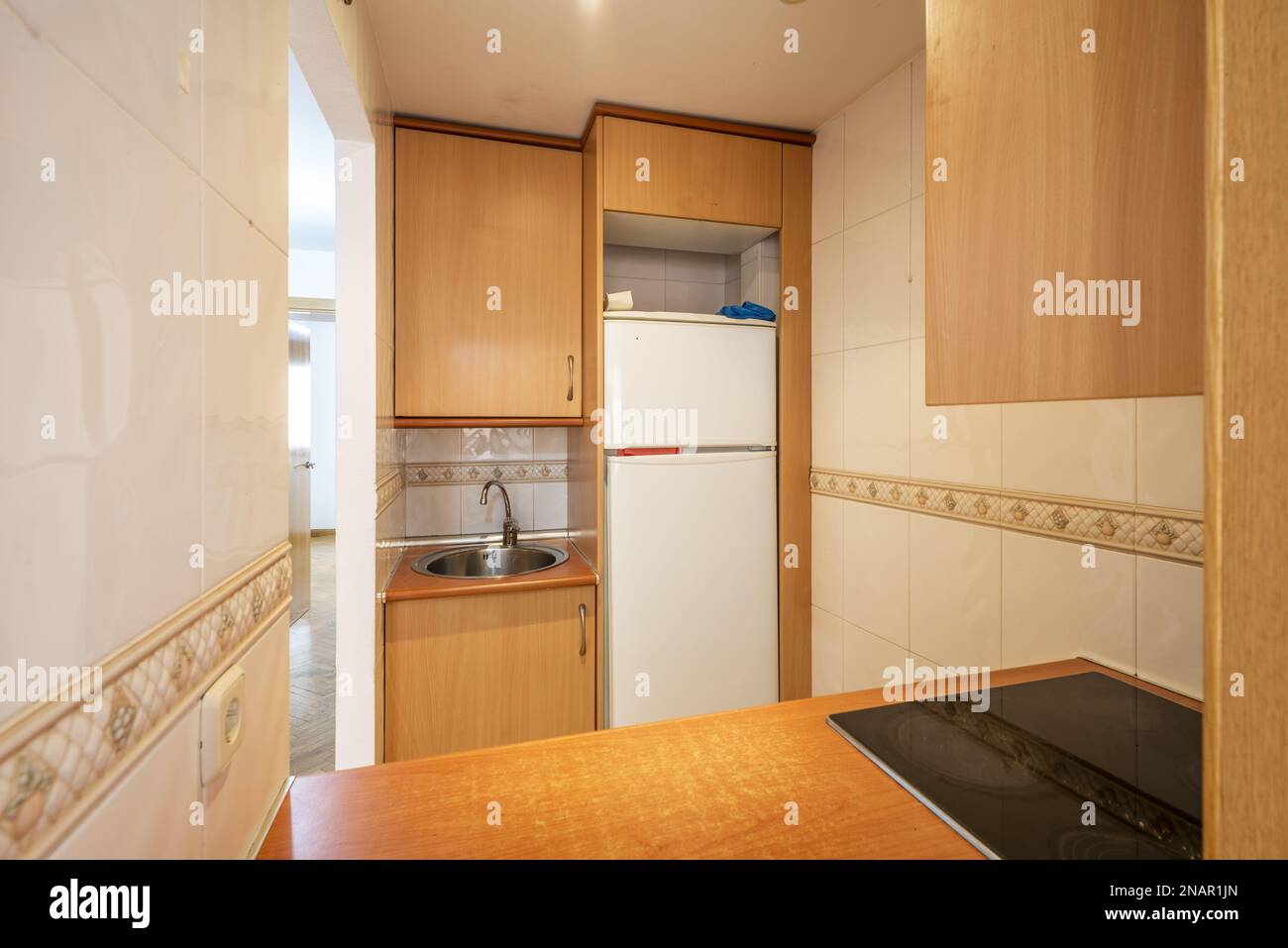 apartment kitchen with wood-colored cabinets, pass-thru window above ...