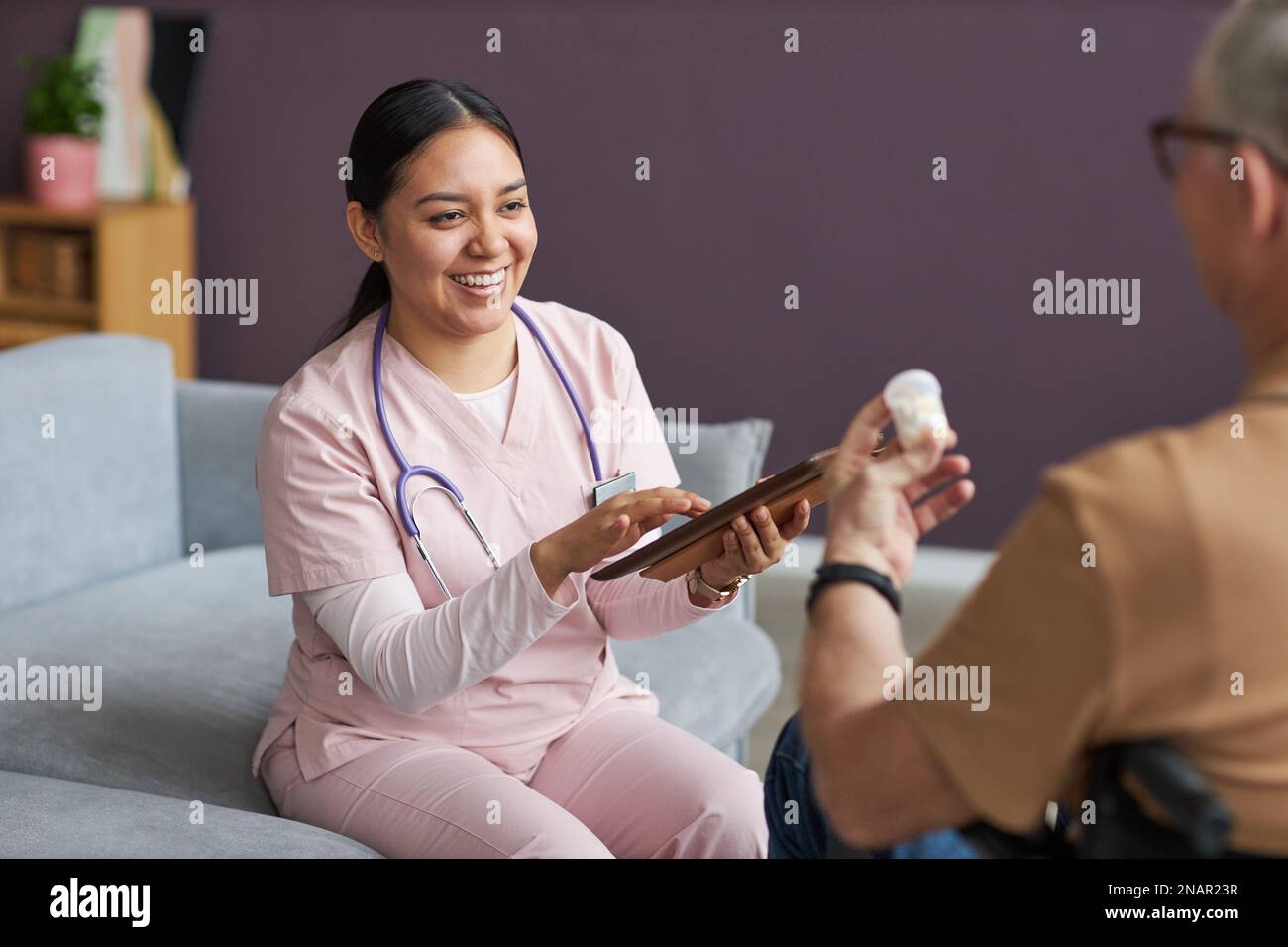 Smiling nurse using digital tablet and explaining her senior patient ...