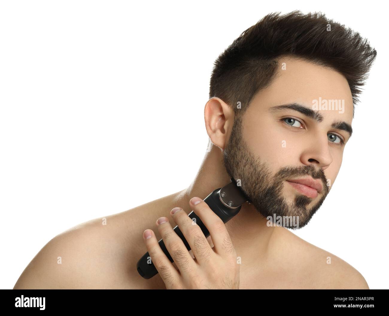 Handsome young man shaving with electric trimmer on white background ...