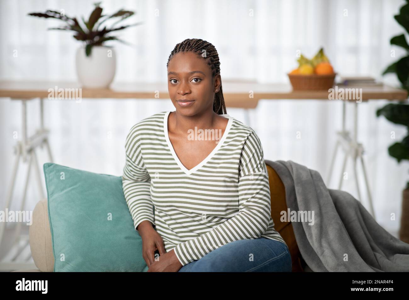 Beautiful young black woman posing on couch in living room Stock Photo ...