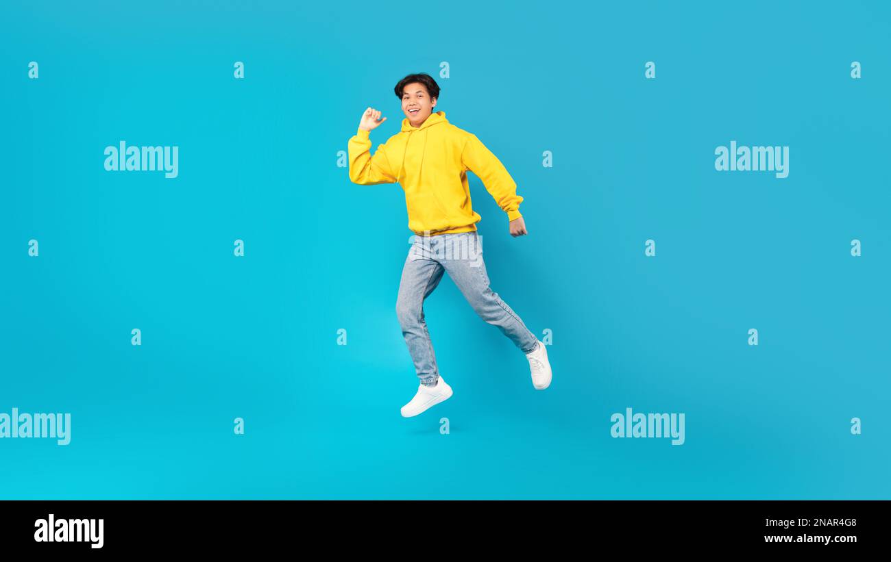Joyful Chinese Teen Boy Jumping Smiling Posing Over Blue Background ...