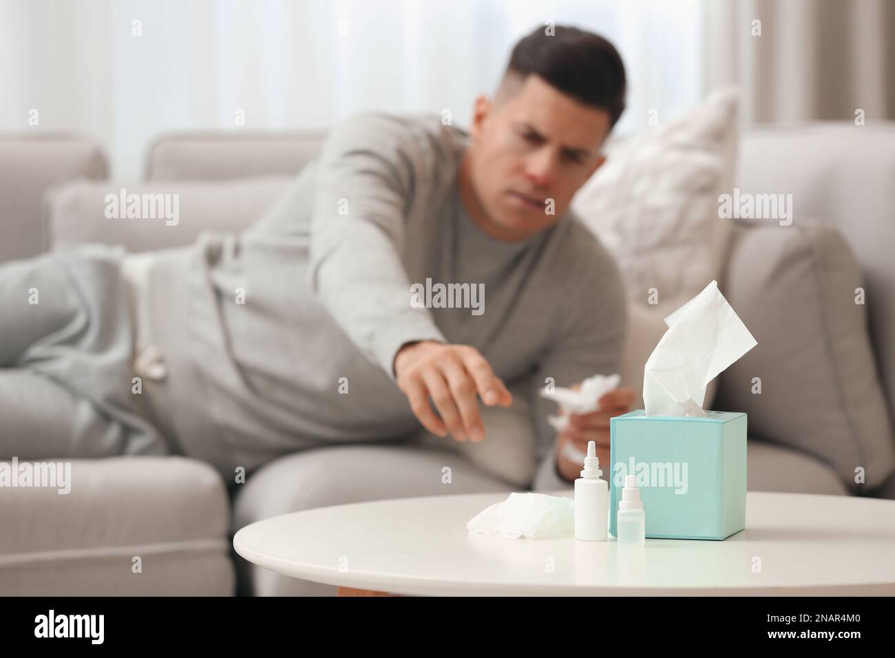 Ill man at home, focus on nasal spray, drops and box of tissues Stock ...