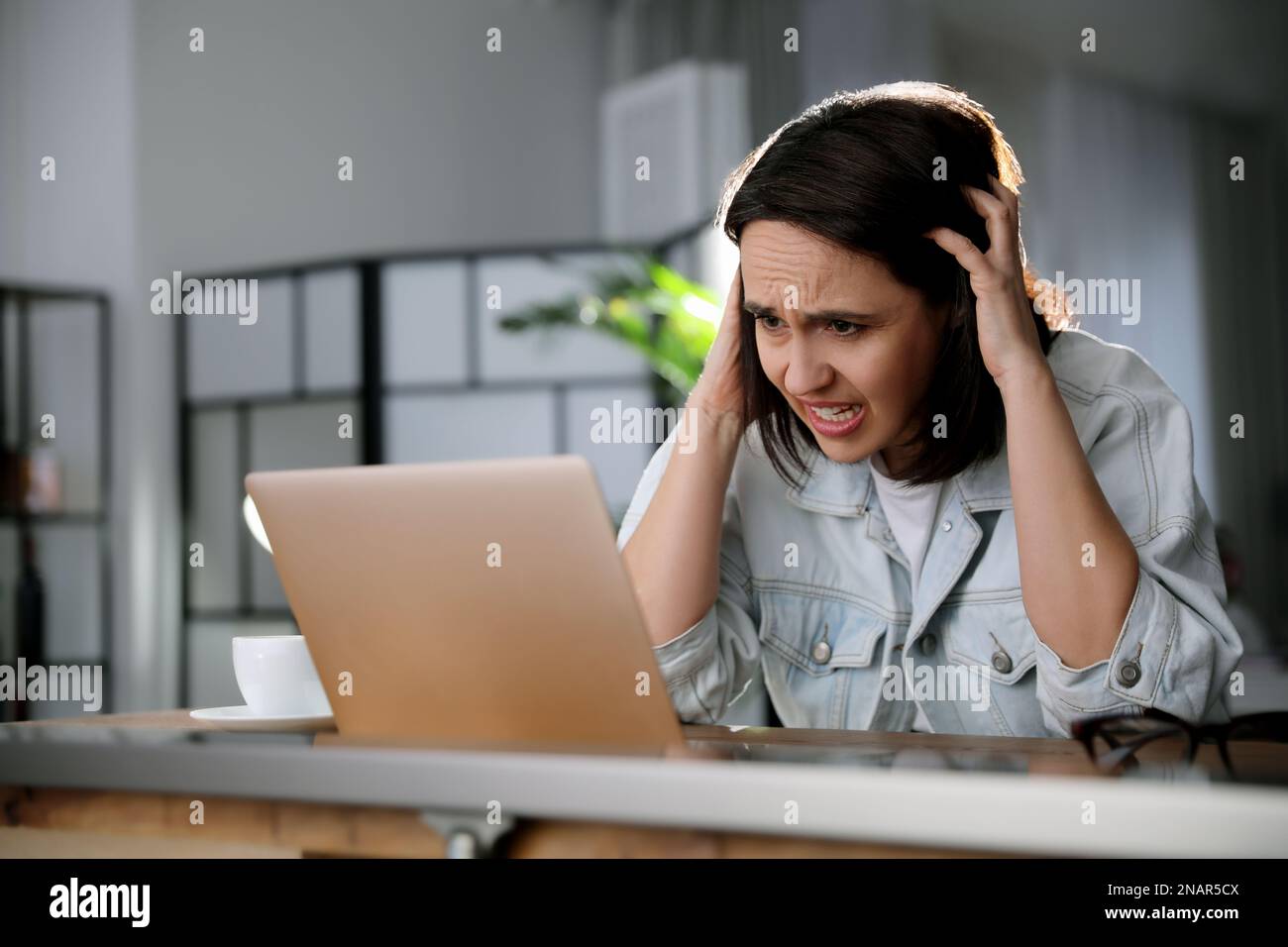 Emotional woman working on laptop in office. Online hate concept Stock ...