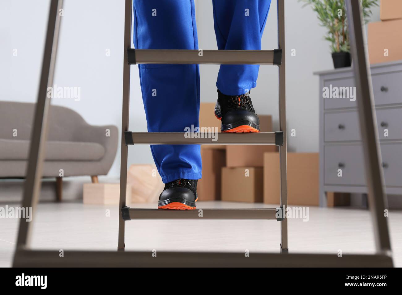 Professional worker climbing up ladder in room, closeup Stock Photo - Alamy