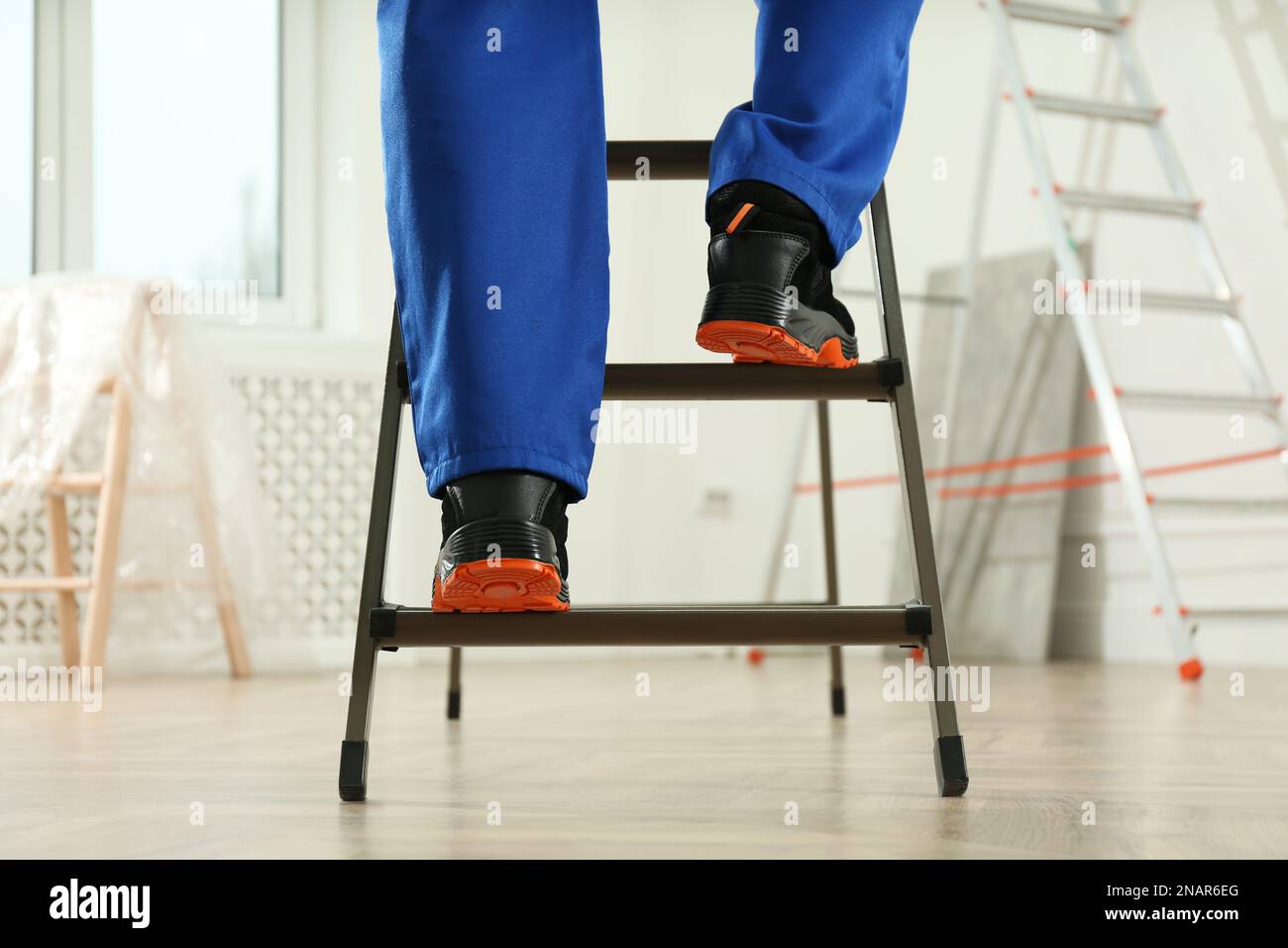 Professional worker climbing up ladder in room, closeup Stock Photo - Alamy