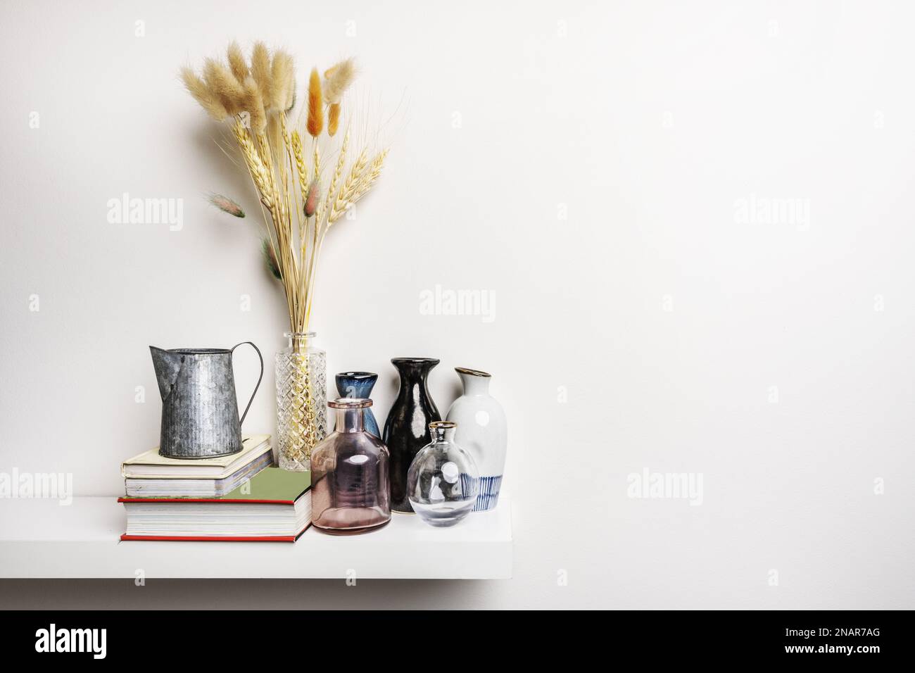 A white shelf with metal, glass and porcelain decorative objects with ...
