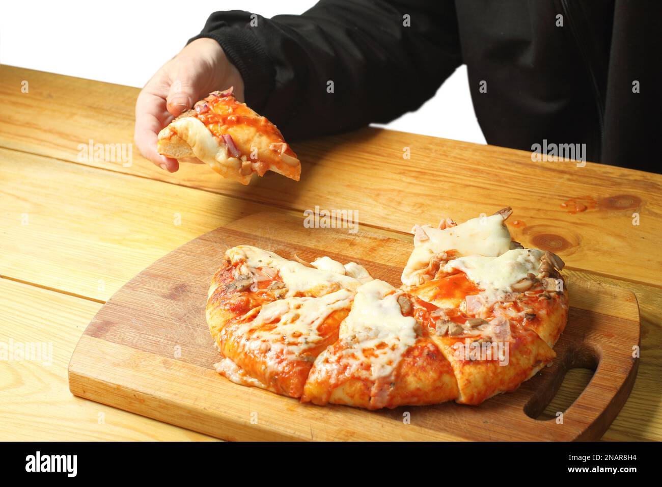 person holding a piece of pizza over the table and white background ...