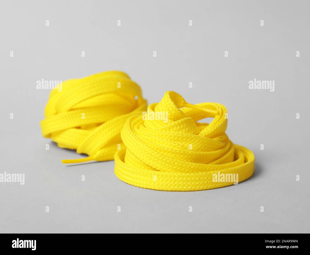 Yellow shoe laces on light grey background Stock Photo - Alamy